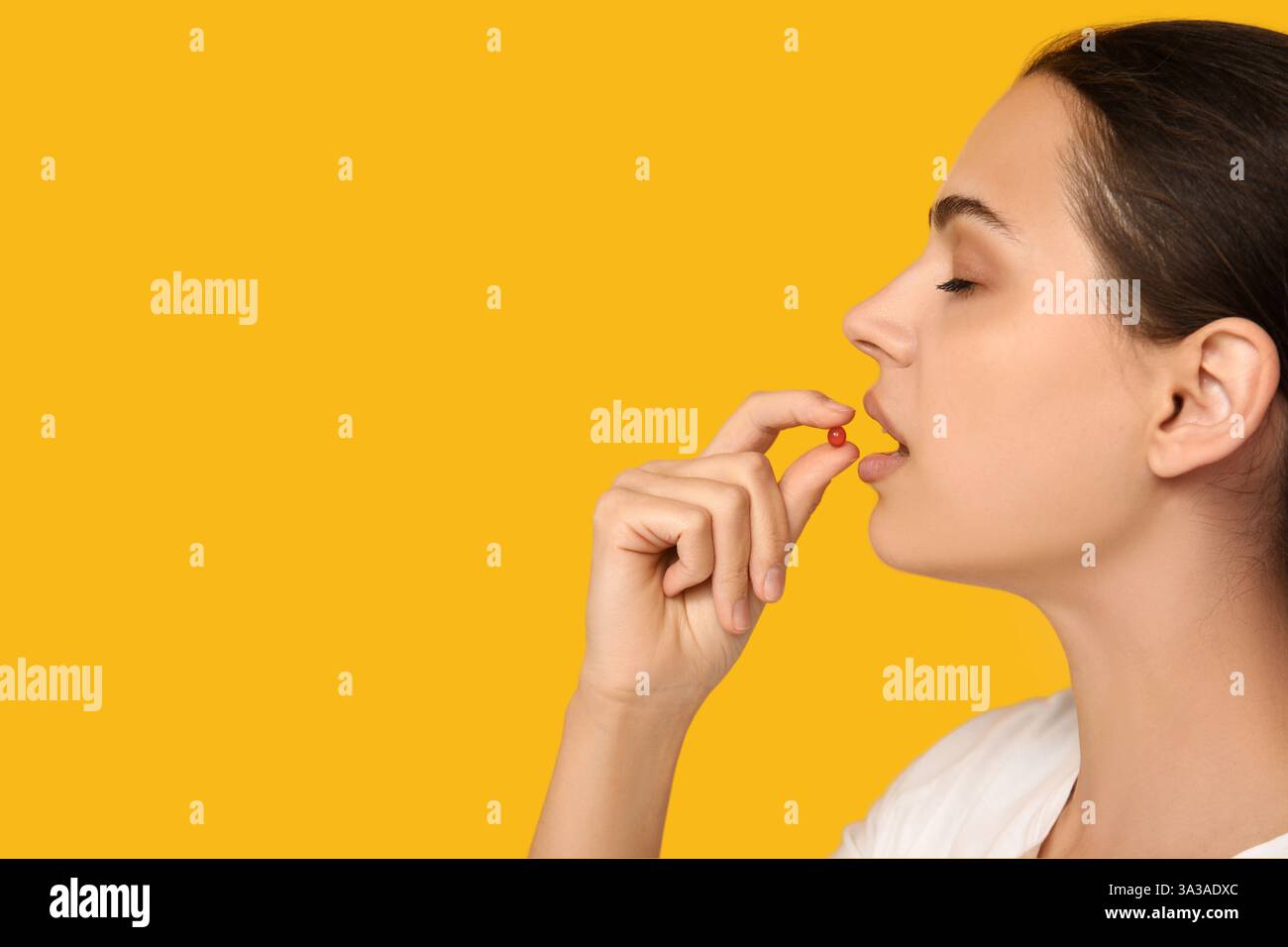 Pretty young woman taking vitamin A capsule on yellow background Stock ...