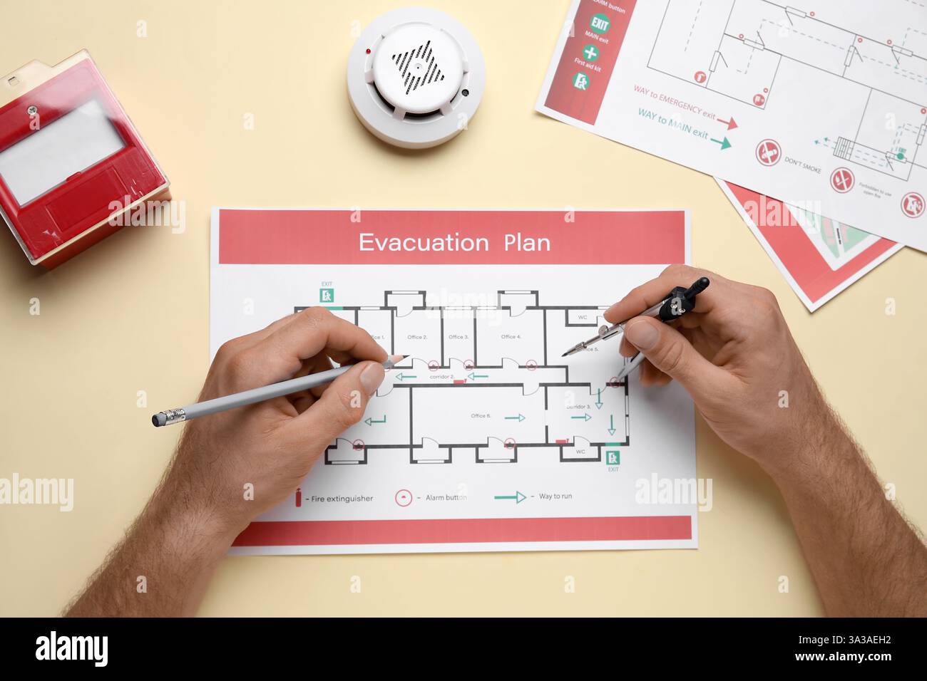 Man with smoke detector and fire call point drawing evacuation plan on ...