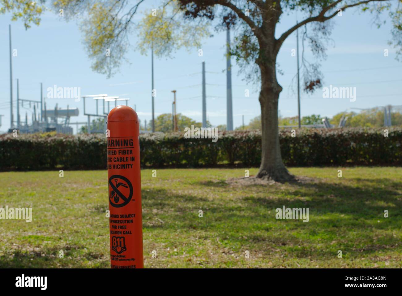Orange and white underground utility marker poles view across green ...