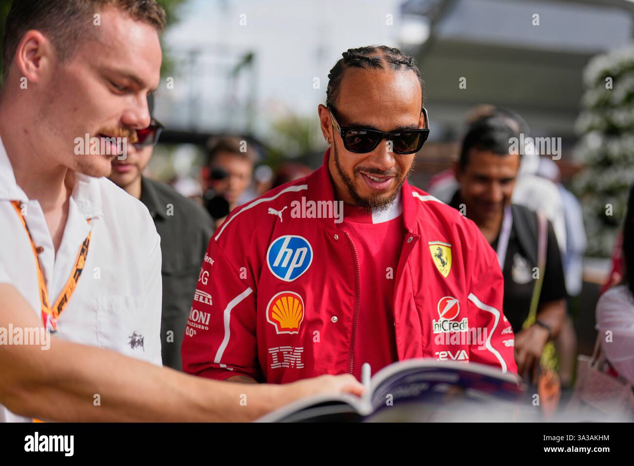 Ferrari driver Lewis Hamilton of Britain signs autographs as he walks ...
