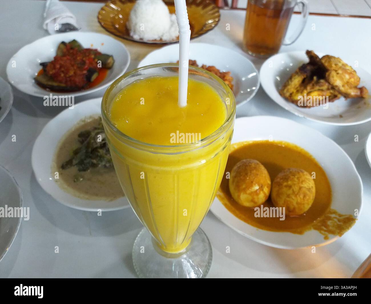 Mango Juice with Indonesian Nasi Padang dishes on a restaurant table ...