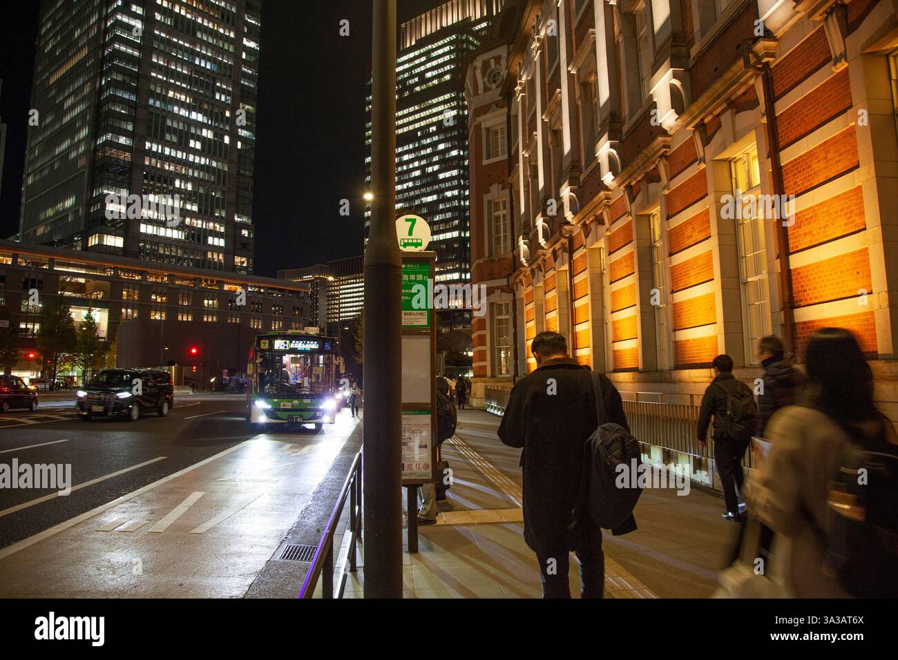 Scene outside Tokyo Station at night with commuters walking on the ...