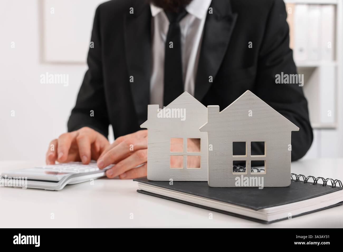 Real estate agent with calculator at white table in office, focus on ...