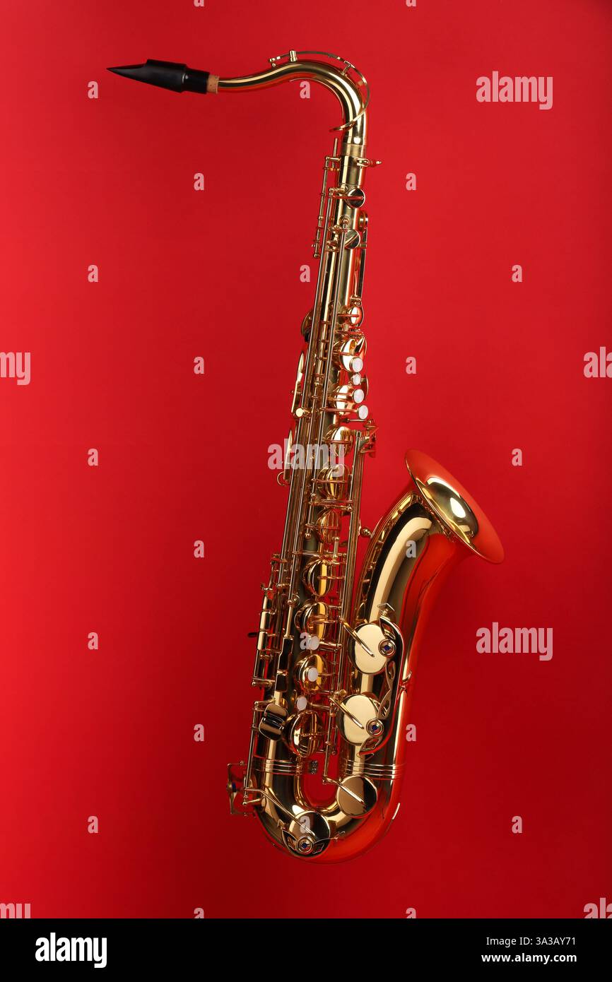 Jazz. One golden saxophone on red background Stock Photo - Alamy