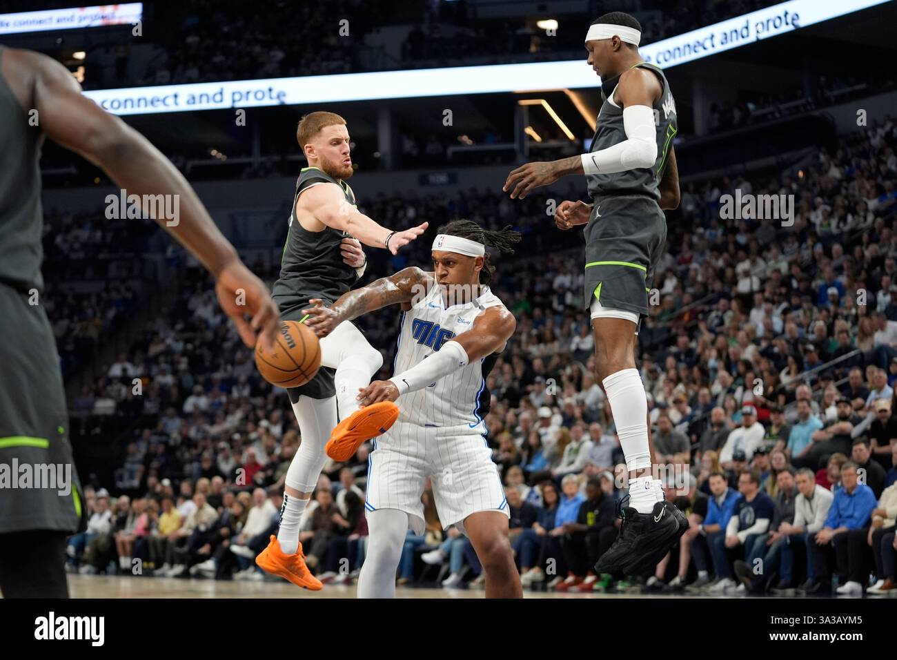 Orlando Magic forward Paolo Banchero (5), center, passes as Minnesota Timberwolves guard Donte ...