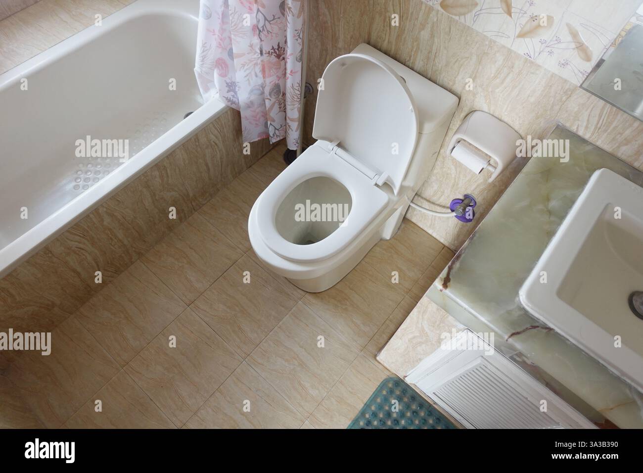 Bathroom interior featuring toilet, bathtub, and sink setup Stock Photo ...
