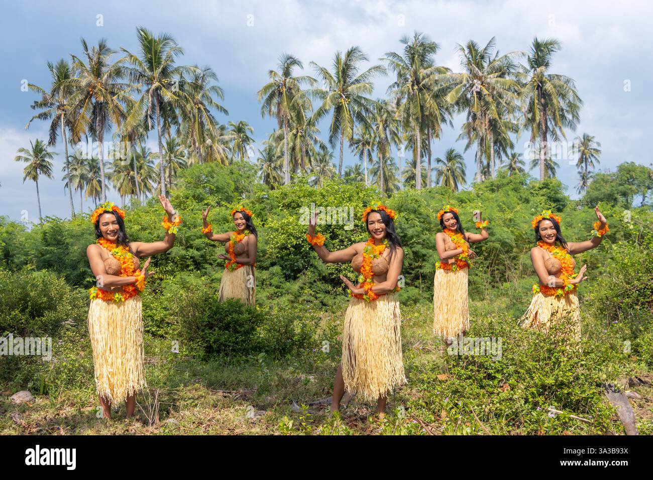 Group of identical hula Hawaiian dancers dancing in tropical nature ...