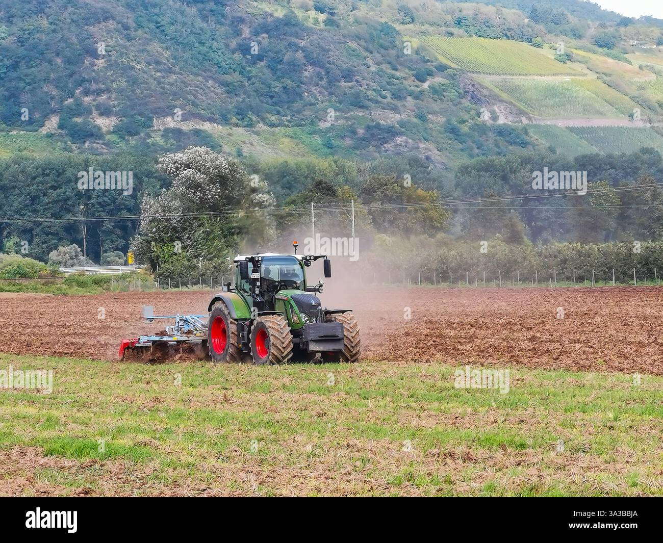 A tractor with a harrow on a wide field harrowing the plowed acre3 ...