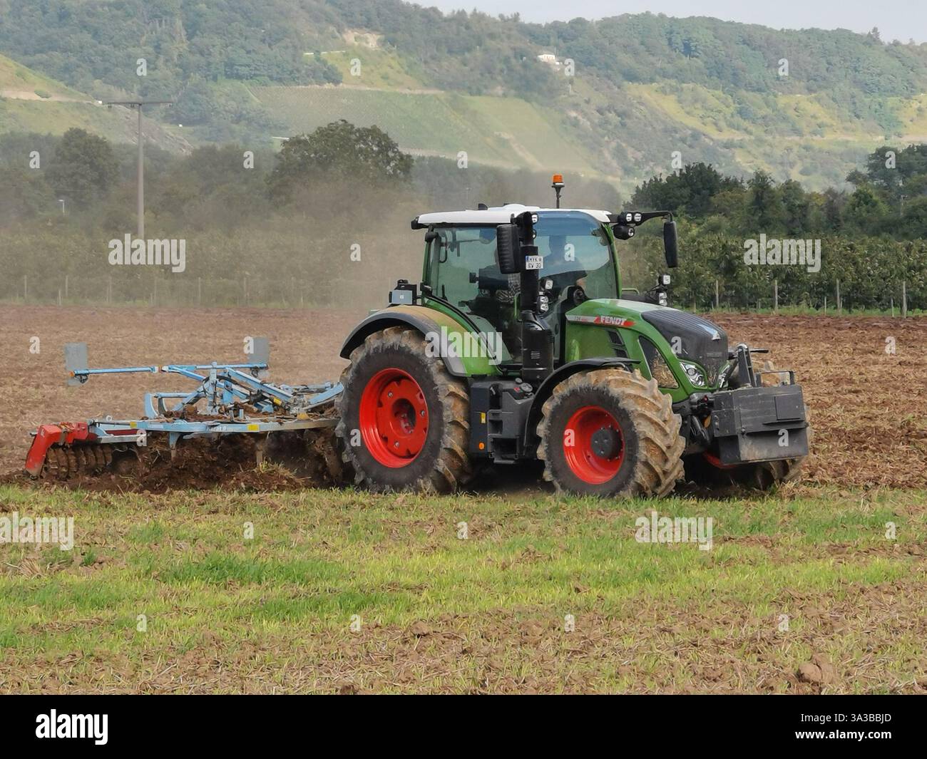A tractor with a harrow on a wide field harrowing the plowed acre Stock ...