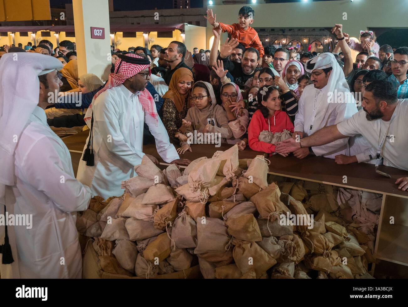 Doha Ramadan Garangao Festival 2025 Qatari men distributing bags of ...