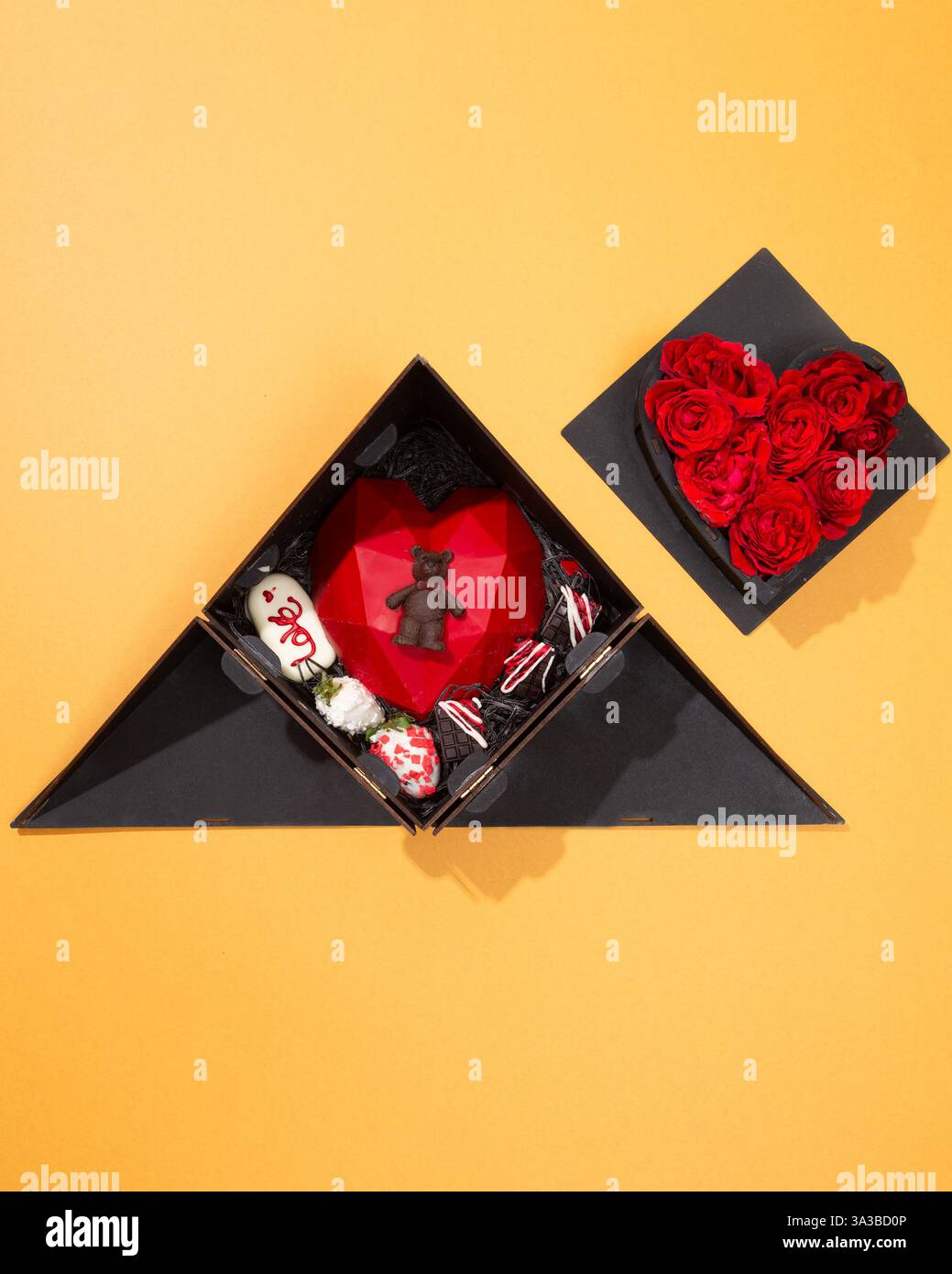 Open black triangle gift box revealing a chocolate heart, teddy bear ...