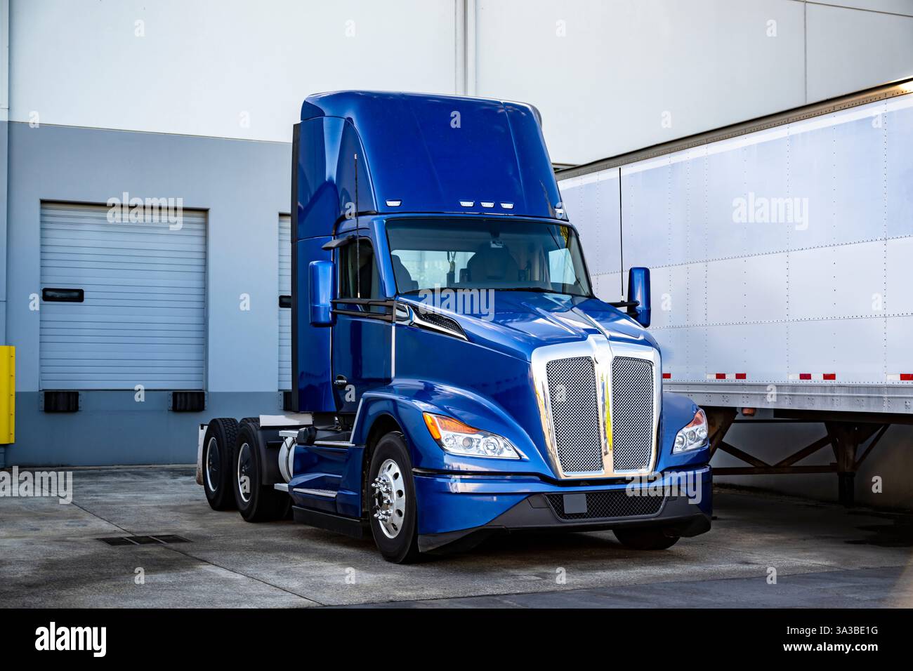 Industrial grade blue big rig day cab local haul semi truck with huge roof spoiler standing ...