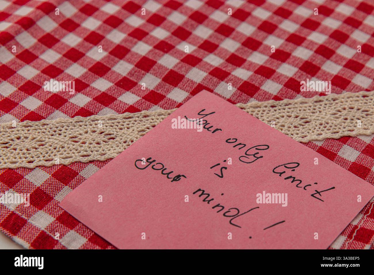 A motivational note is placed on a red and white checkered fabric with ...