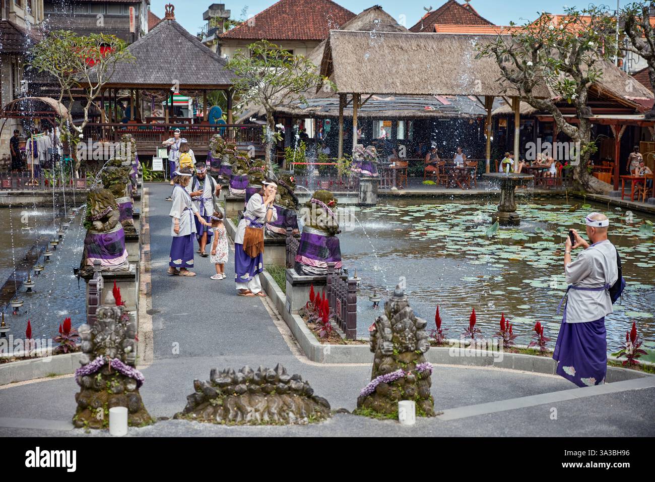 Tourists wearing sarongs visit Ubud Water Palace at Saraswati Temple ...