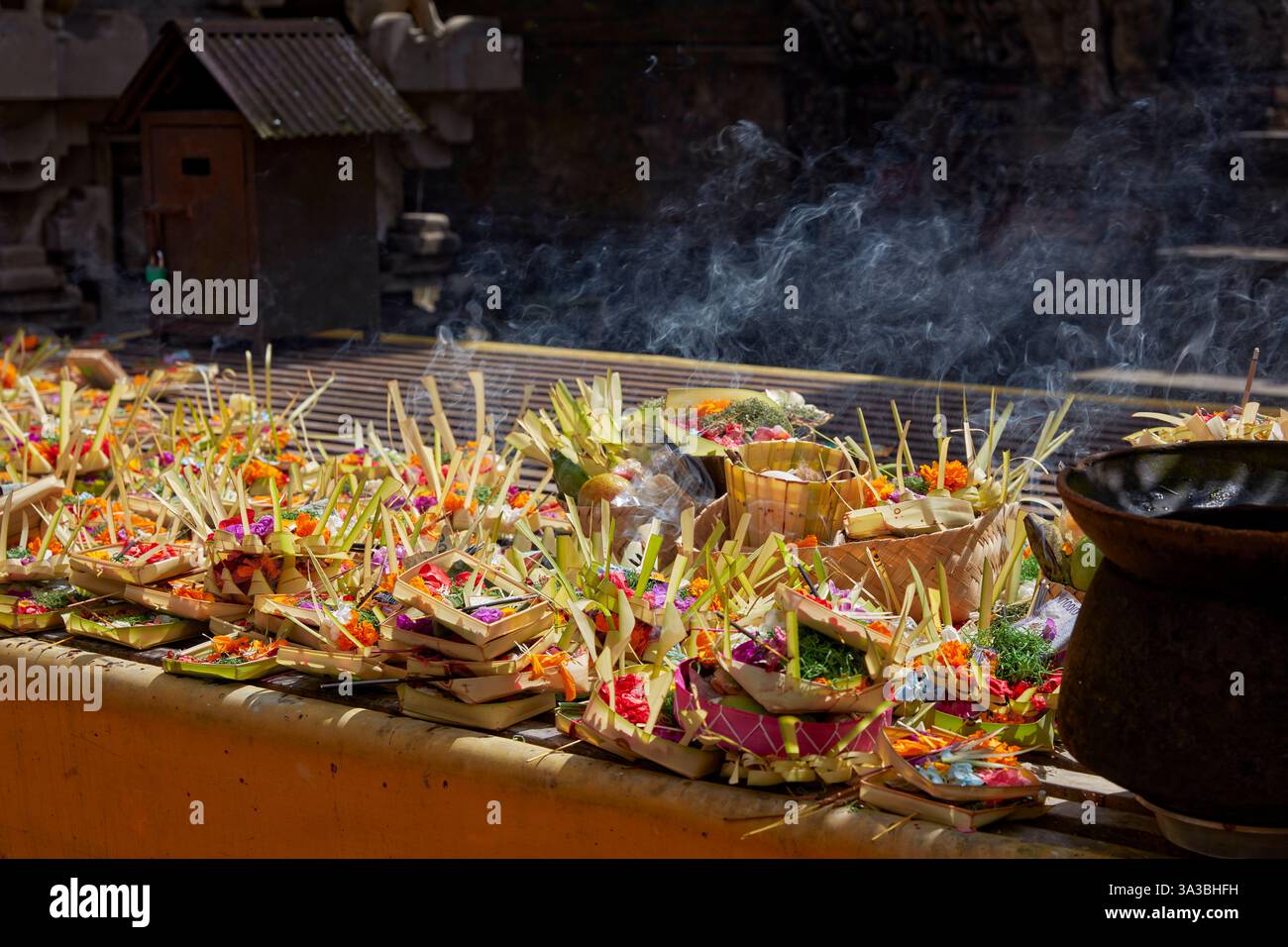 An altar table with traditional Balinese offerings and smoking incense ...