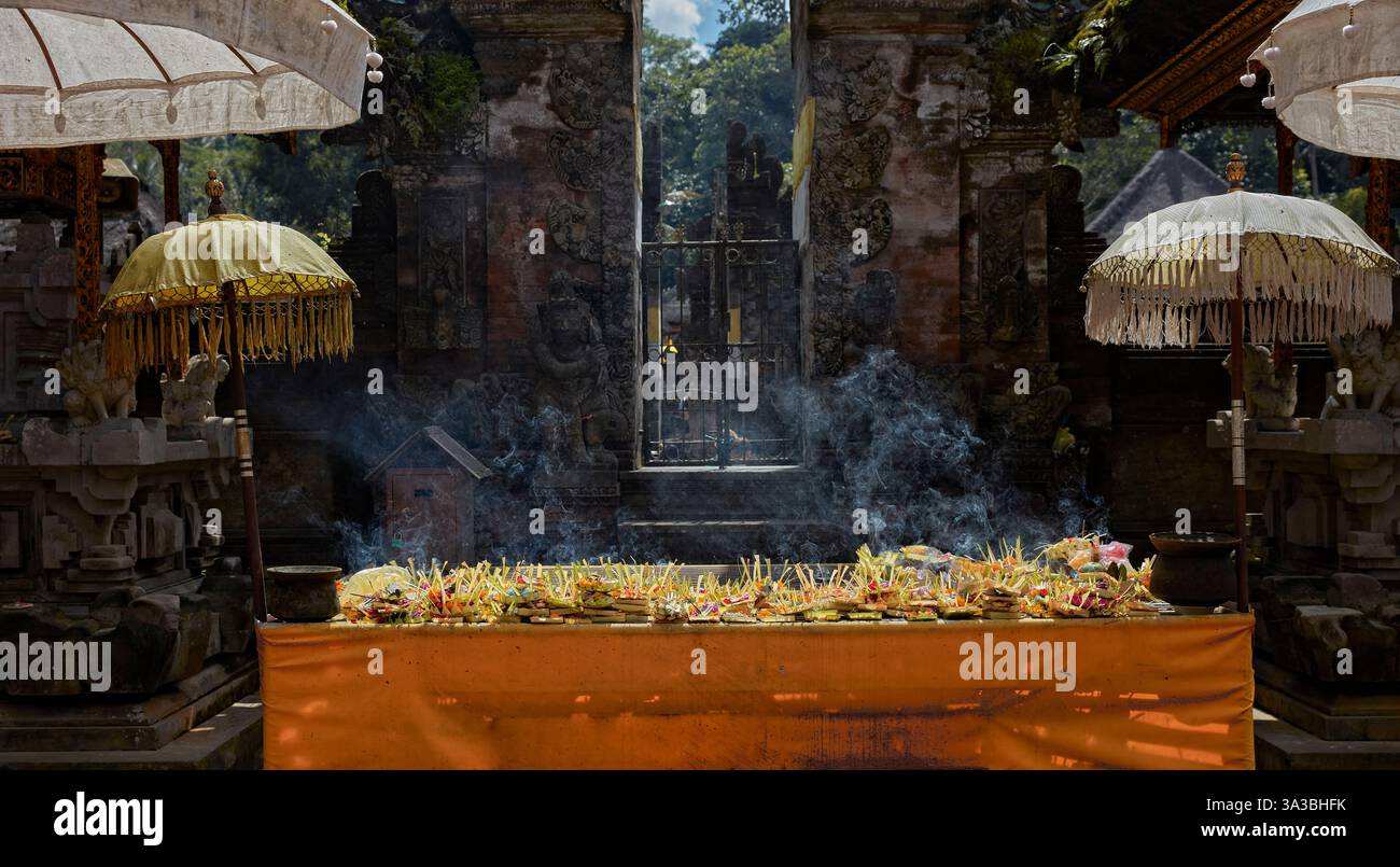 An altar table with traditional Balinese offerings and smoking incense ...