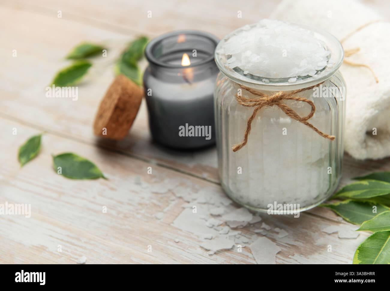 Magnesium bath flakes in a glass jar tied with twine next to a burning ...