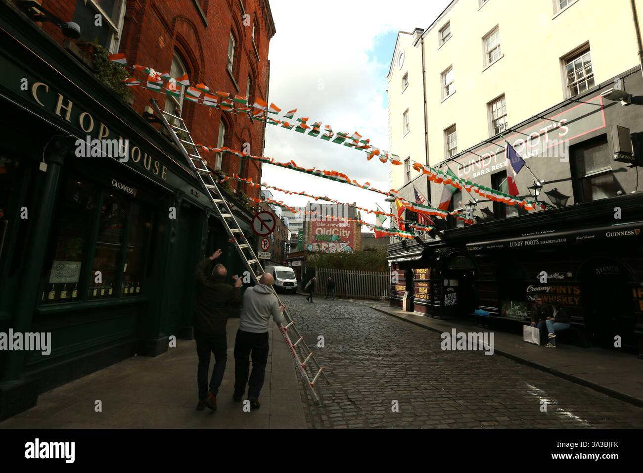 Dublin, Ireland - 12th March 2025 - Men with a ladder putting up green ...