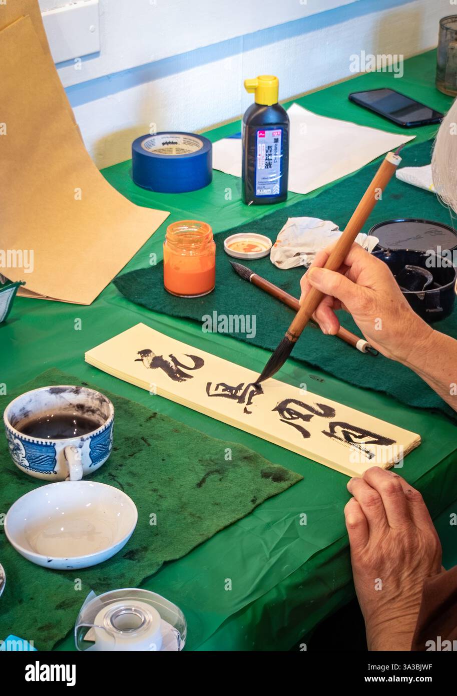 Artist s hand guides a calligraphy brush, creating traditional Japanese ...