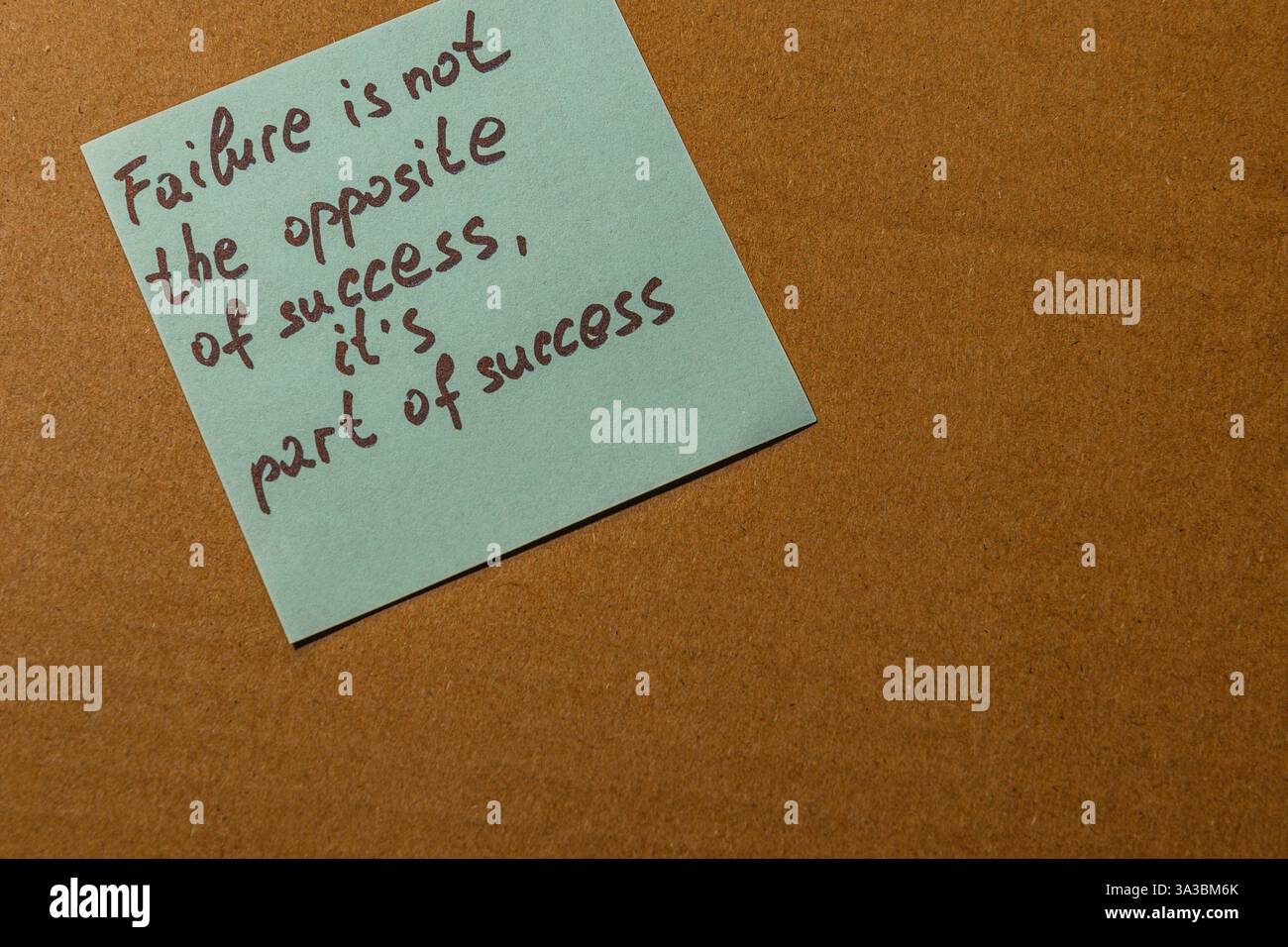 A light blue sticky note is placed on a brown surface, featuring a ...