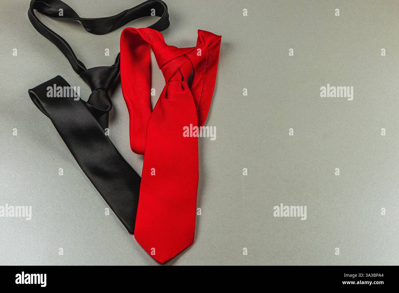 Two ties, one red and one black, are artistically arranged on a smooth ...