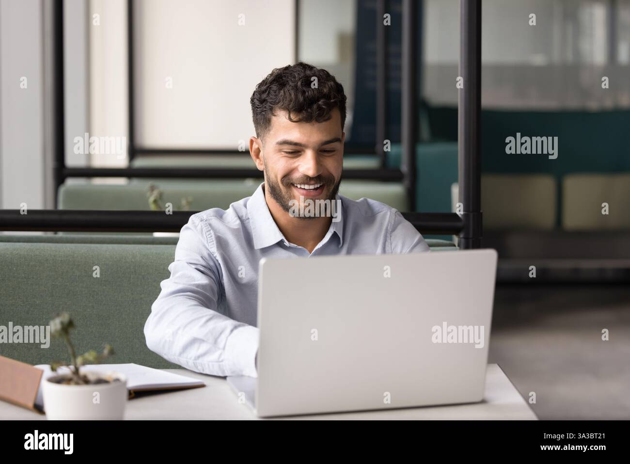 Smiling Arabian employee writing emails on laptop Stock Photo - Alamy