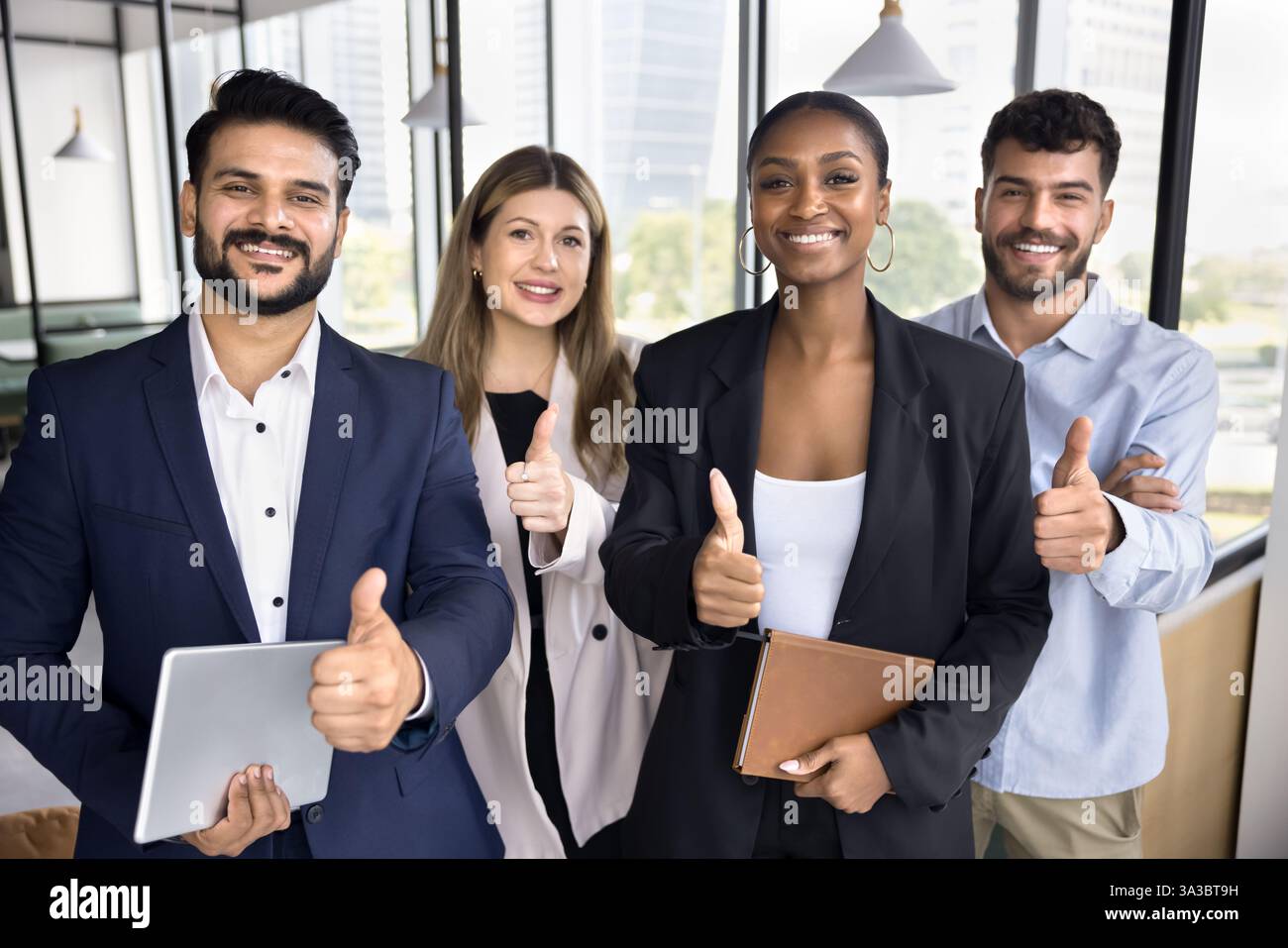 Group of four young and ambitious professionals giving thumbs-up ...
