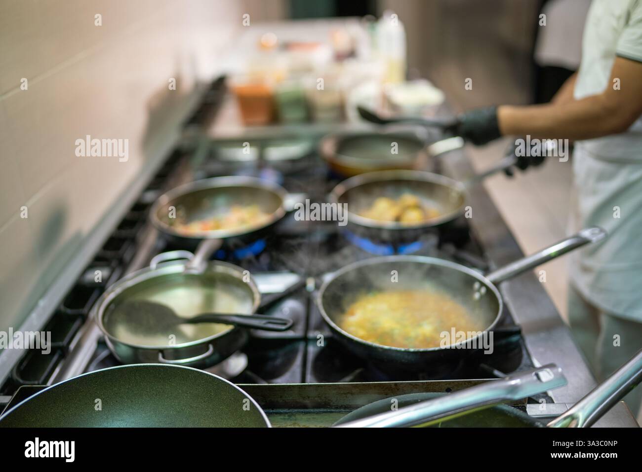 Steam rising from a pan of indian food being stirred by a chef in a ...