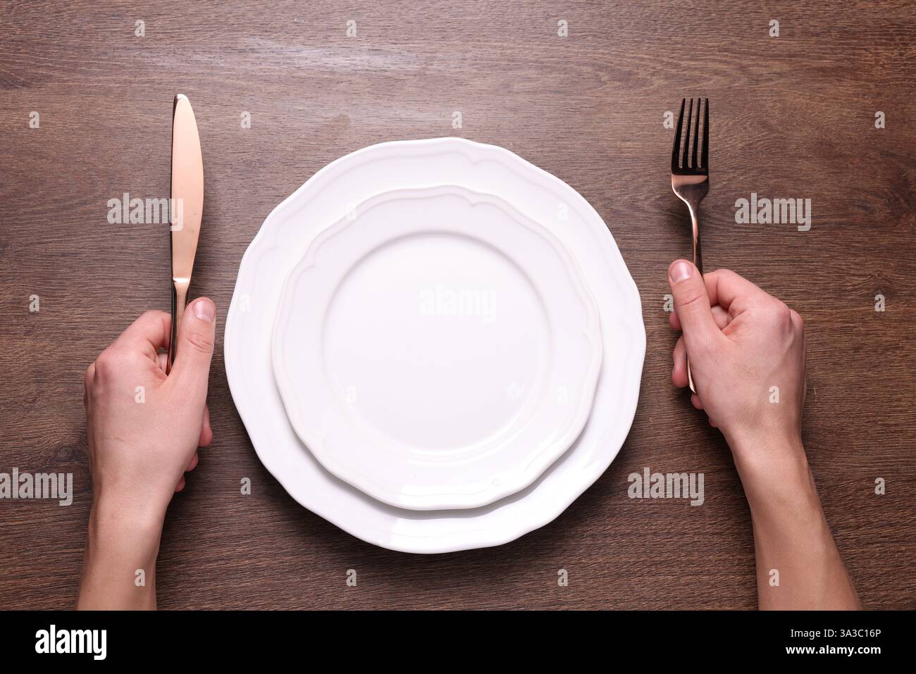 Man with cutlery and clean plates at wooden table, top view Stock Photo ...