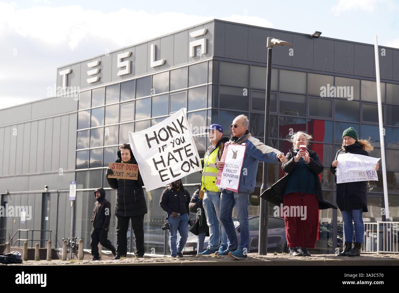 People take part in a protest outside of the Tesla centre at Park Royal ...
