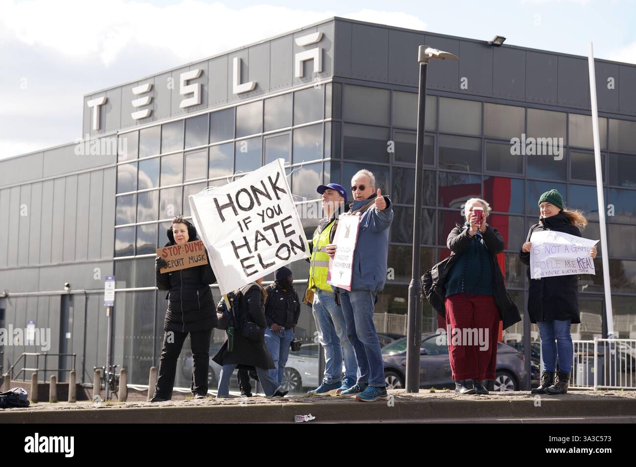 People take part in a protest outside of the Tesla centre at Park Royal ...