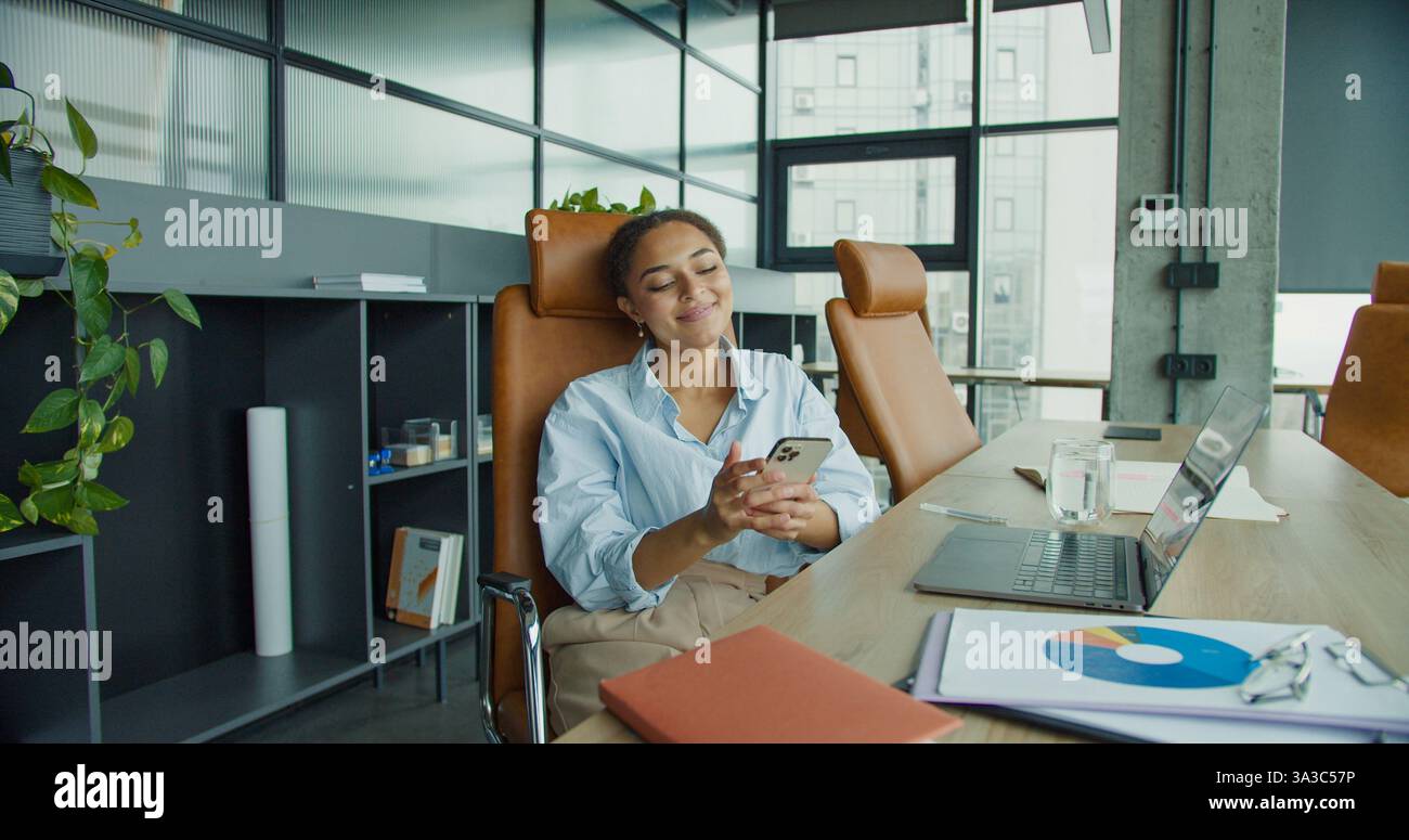 A young professional woman multitasking in a modern office, talking on ...