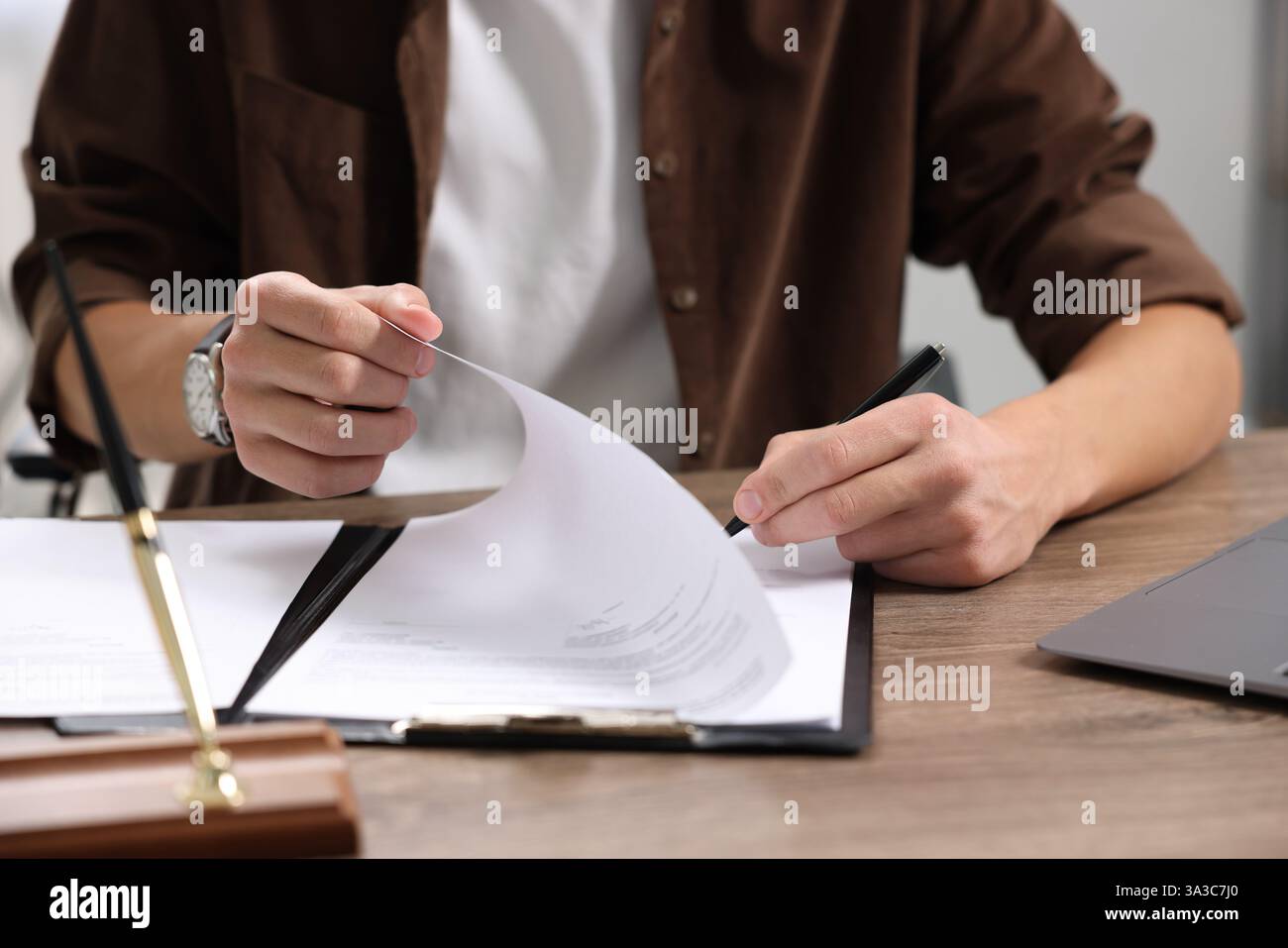 Client signing notarial document at wooden table in office, closeup ...