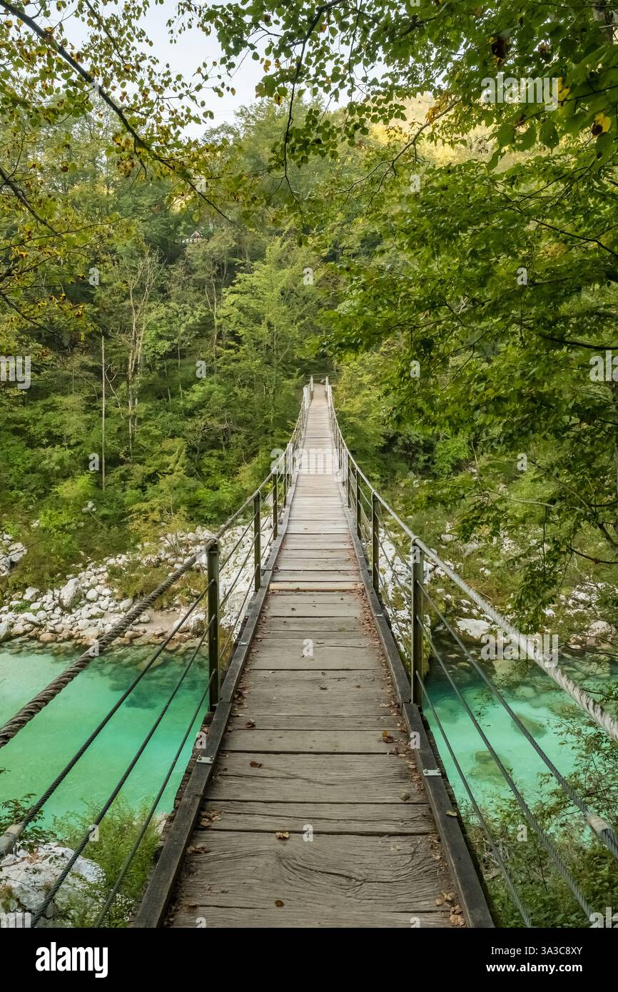 A suspension bridge spans the emerald waters of the Soca River in ...