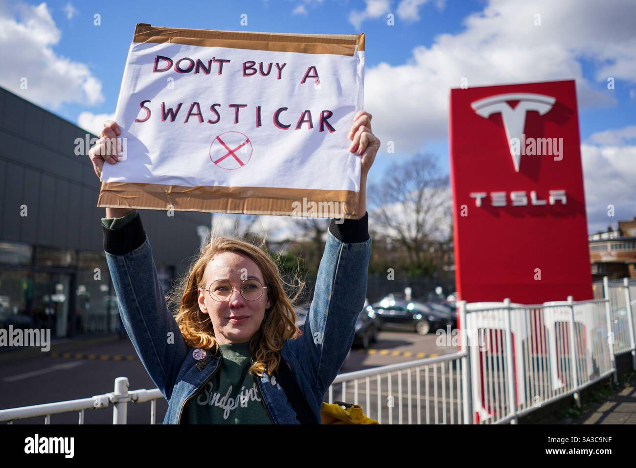 A demonstrator holds a placard outside a Tesla centre, as part of a ...