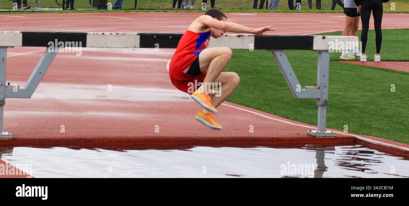 Runner leaps over a barrier and flips into the water while competing in ...