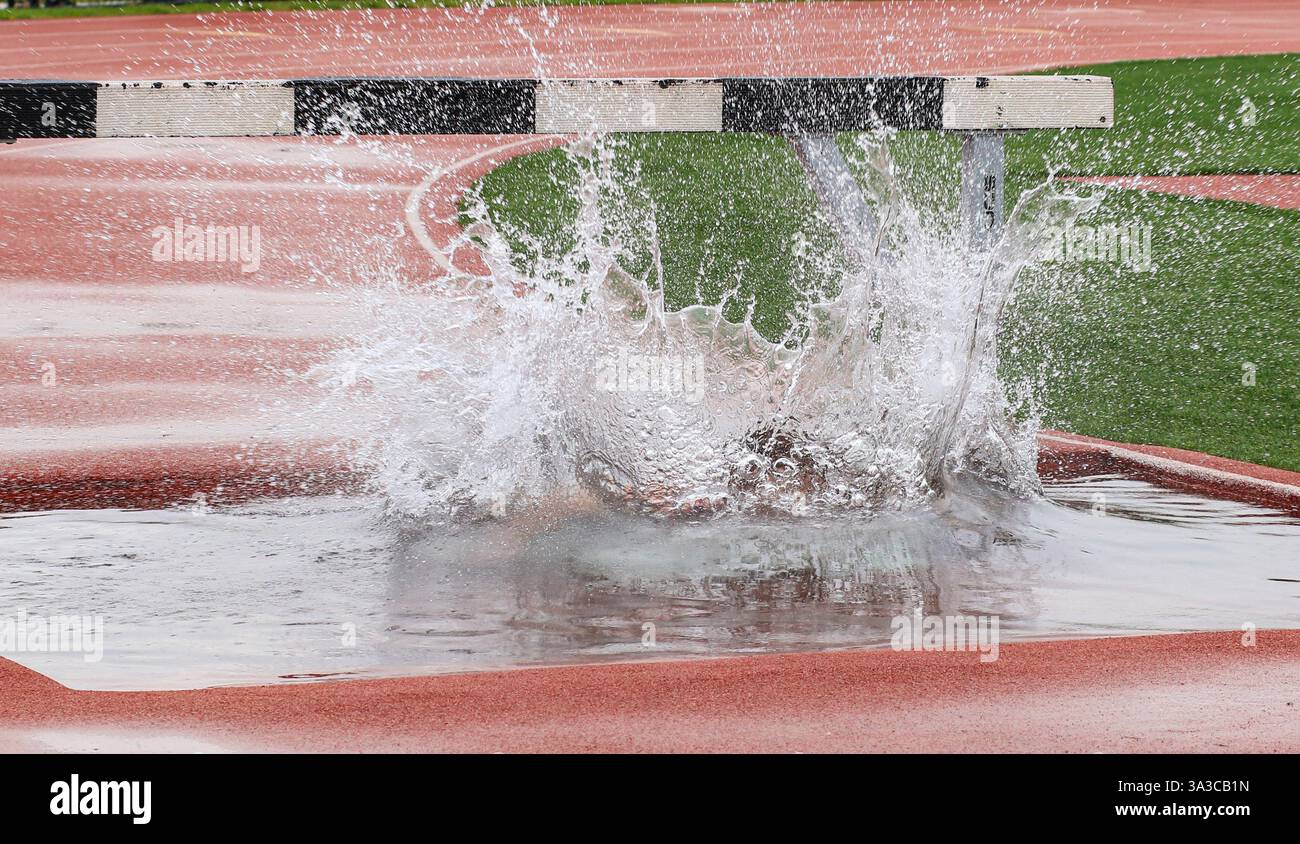 Athlete makes a dynamic jump into the water pit at a sports facility ...