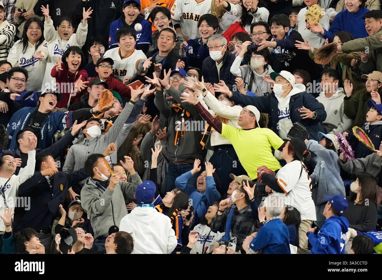 Fans reach out to catch a tossed into the stands by a player during the ...