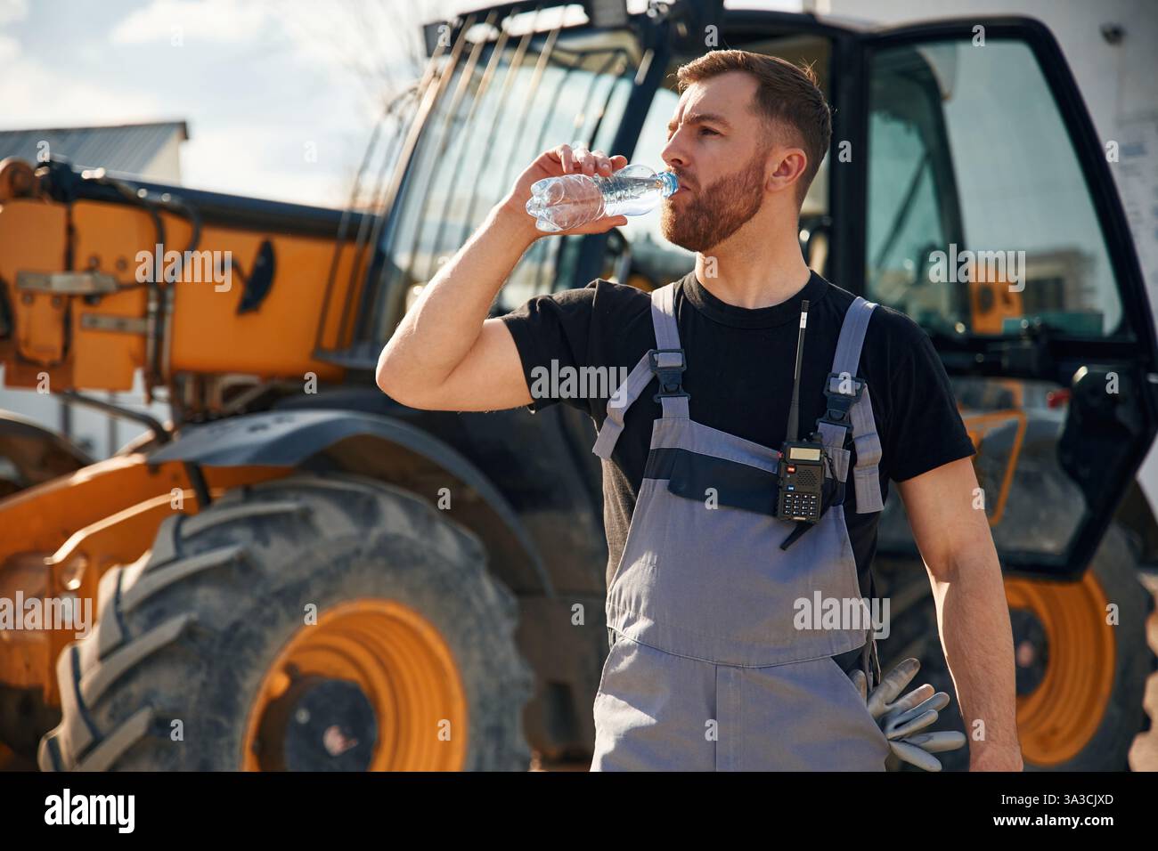 Drinking water, taking a break, tired. Man is with tractor ...