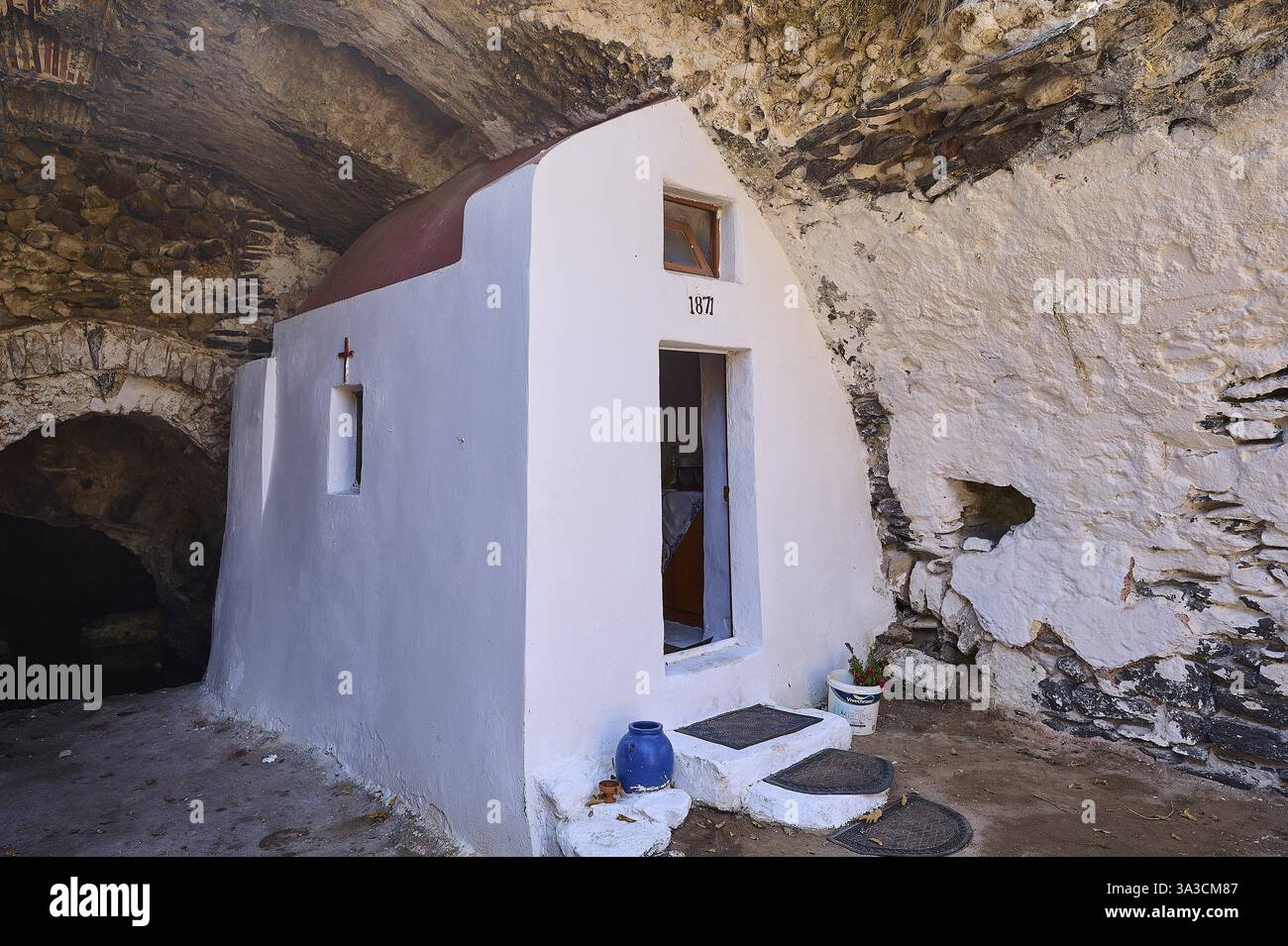Simple white chapel in a rustic cave with minimalist furnishings ...
