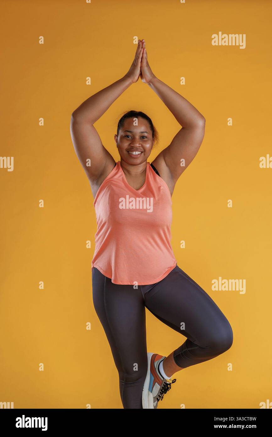 Yoga stance, with hands up. African American woman is in the studio ...
