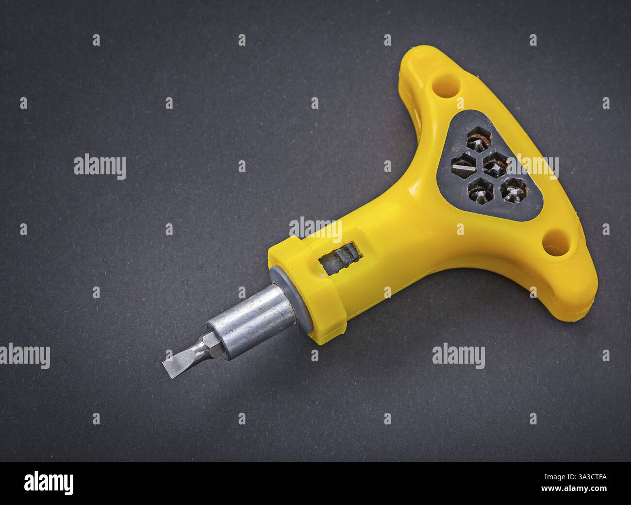 Yellow reversible screwdriver wih bits on black background Stock Photo ...