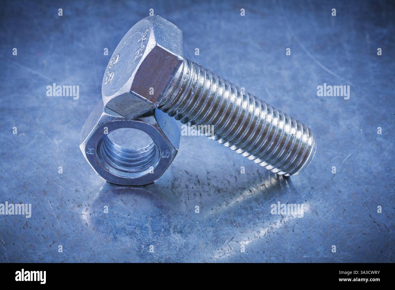 Threaded screwbolt and construction nut on metallic background top view ...