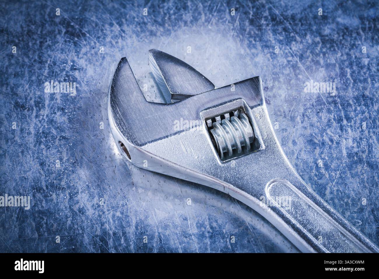Stainless adjustable spanner on scratched metallic background ...