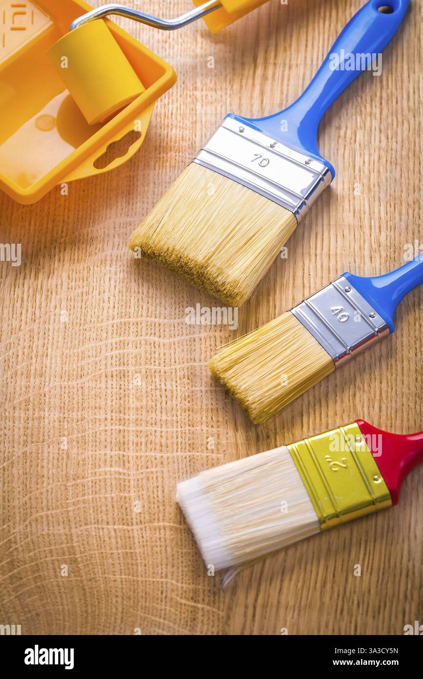 Three paint brushes roller and tray on wooden oard Stock Photo - Alamy