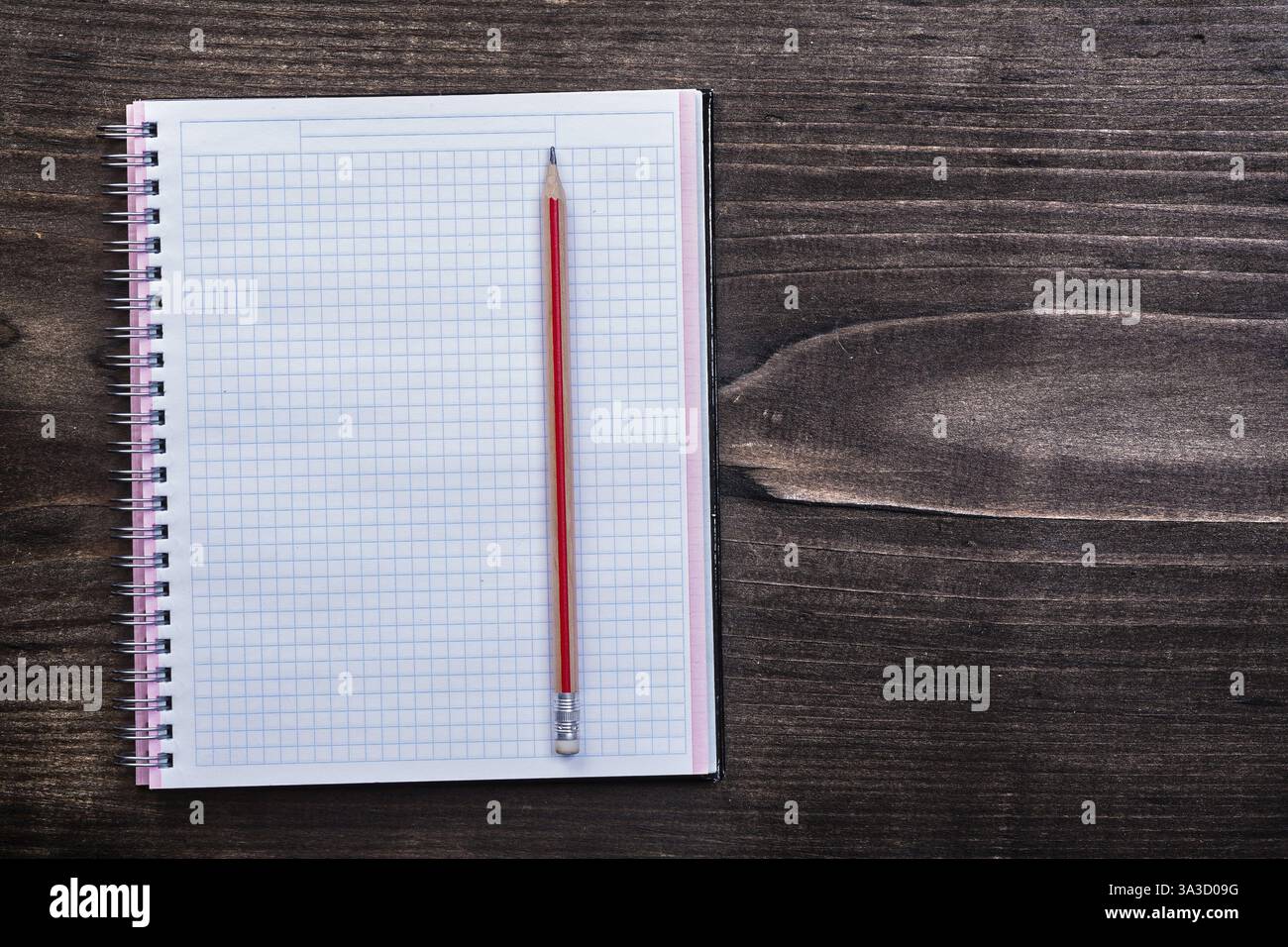 White checked copybook with red pencil on pine brown wooden board ...