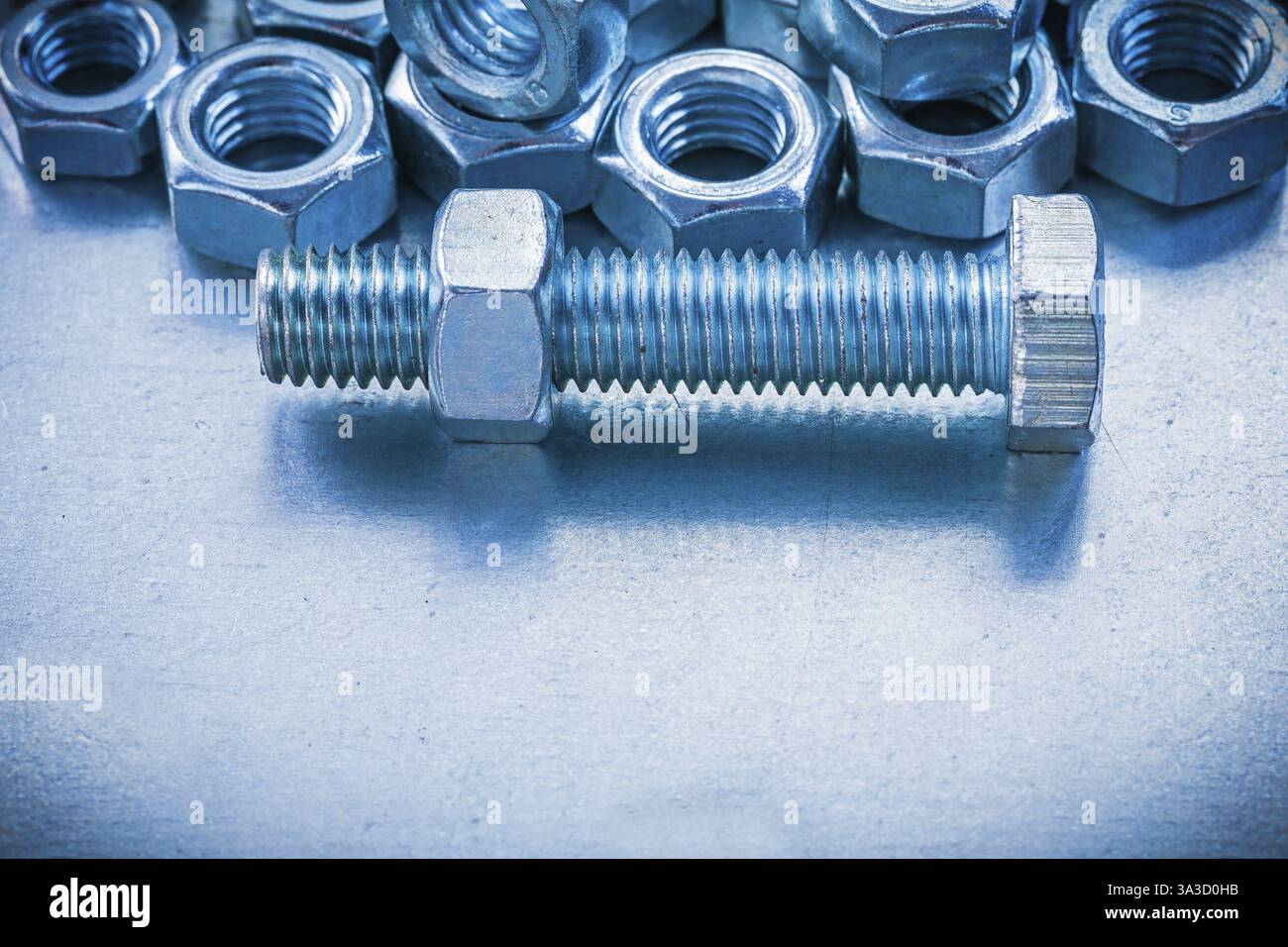 Vertical view of threaded screw nuts and bolts on metallic background ...