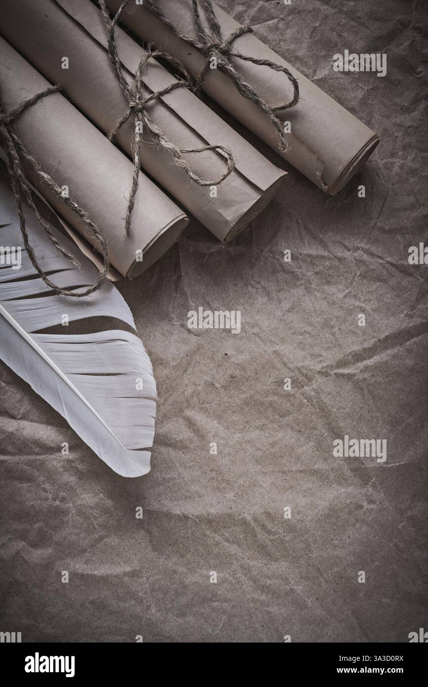 Stack of vintage paper scrolls feather on crumpled wrapping sheet Stock ...
