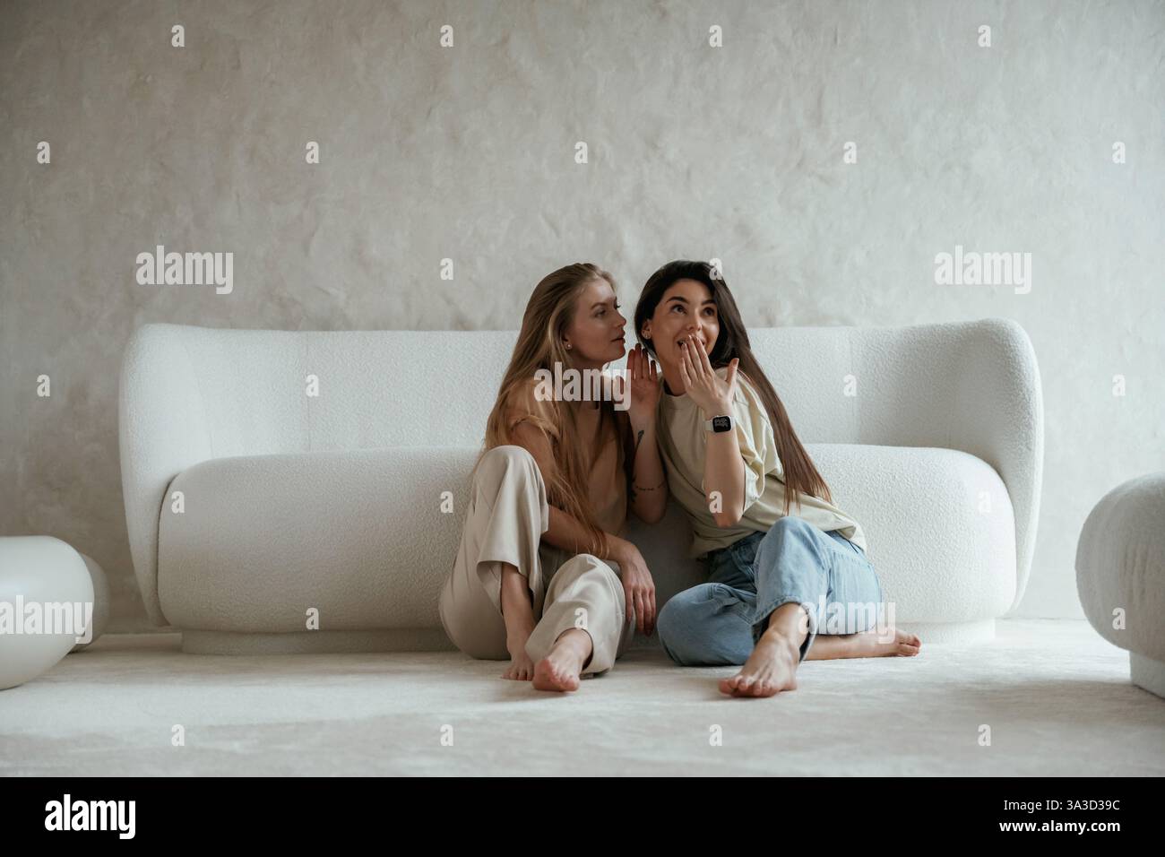 Telling a secret. Two happy young female best friends are indoors Stock ...