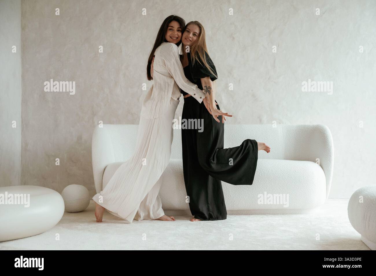 Standing and embracing each other. Two happy young female best friends ...